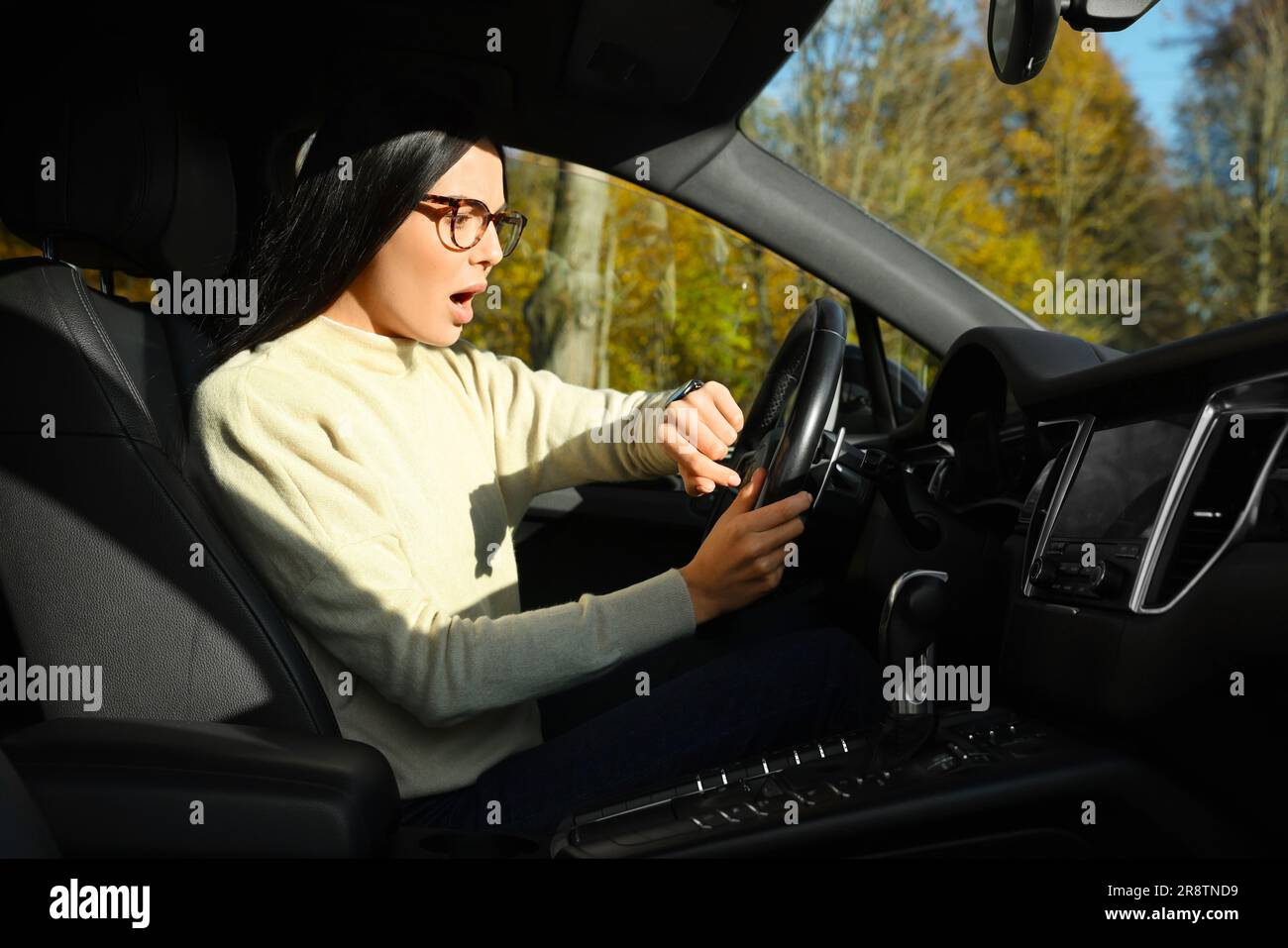 Emotional woman checking time on watch in car. Being late concept Stock ...