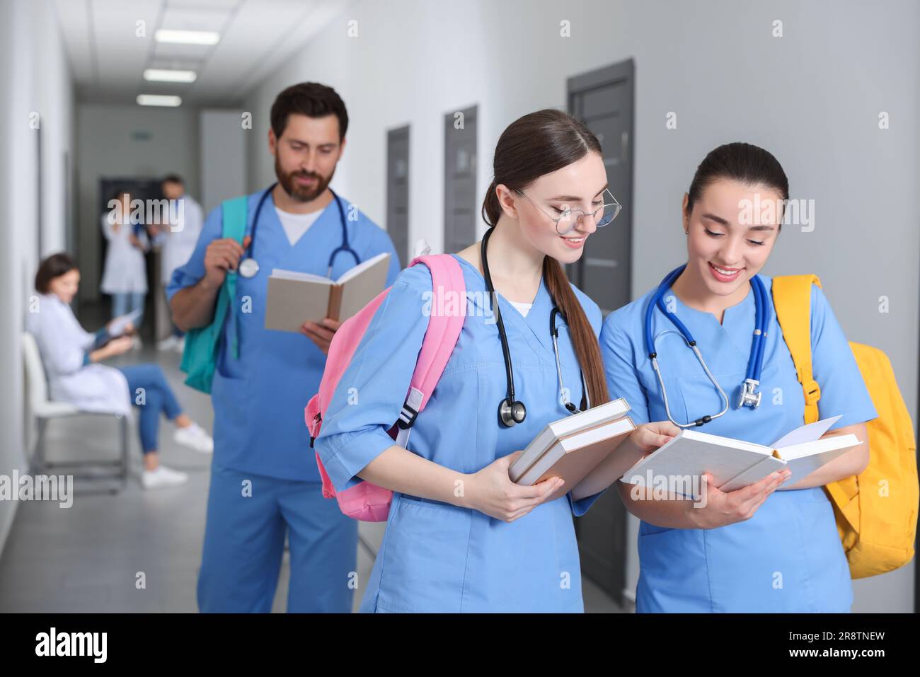 Smart medical students with books in college hallway, space for text ...