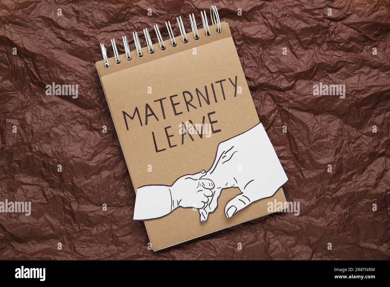 Notepad with words Maternity Leave and cutout of hands on brown ...