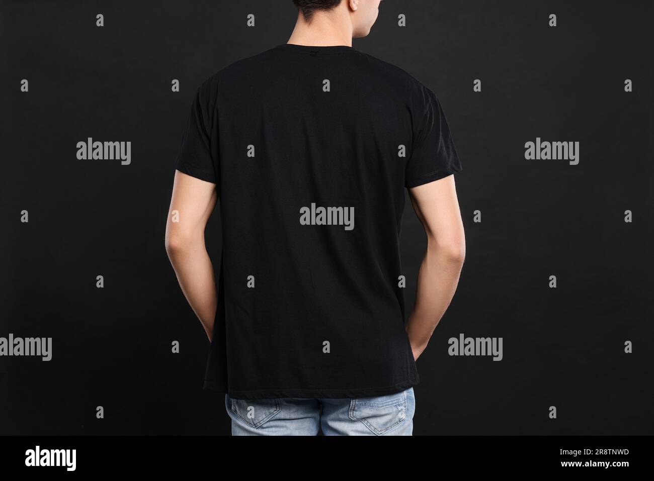 Man wearing stylish t-shirt on black background, back view. Mockup for ...