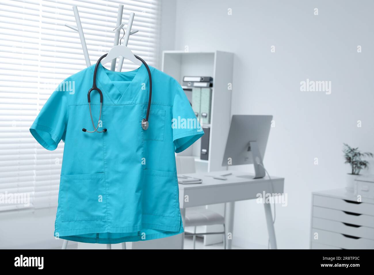 Turquoise medical uniform and stethoscope hanging on rack in clinic ...