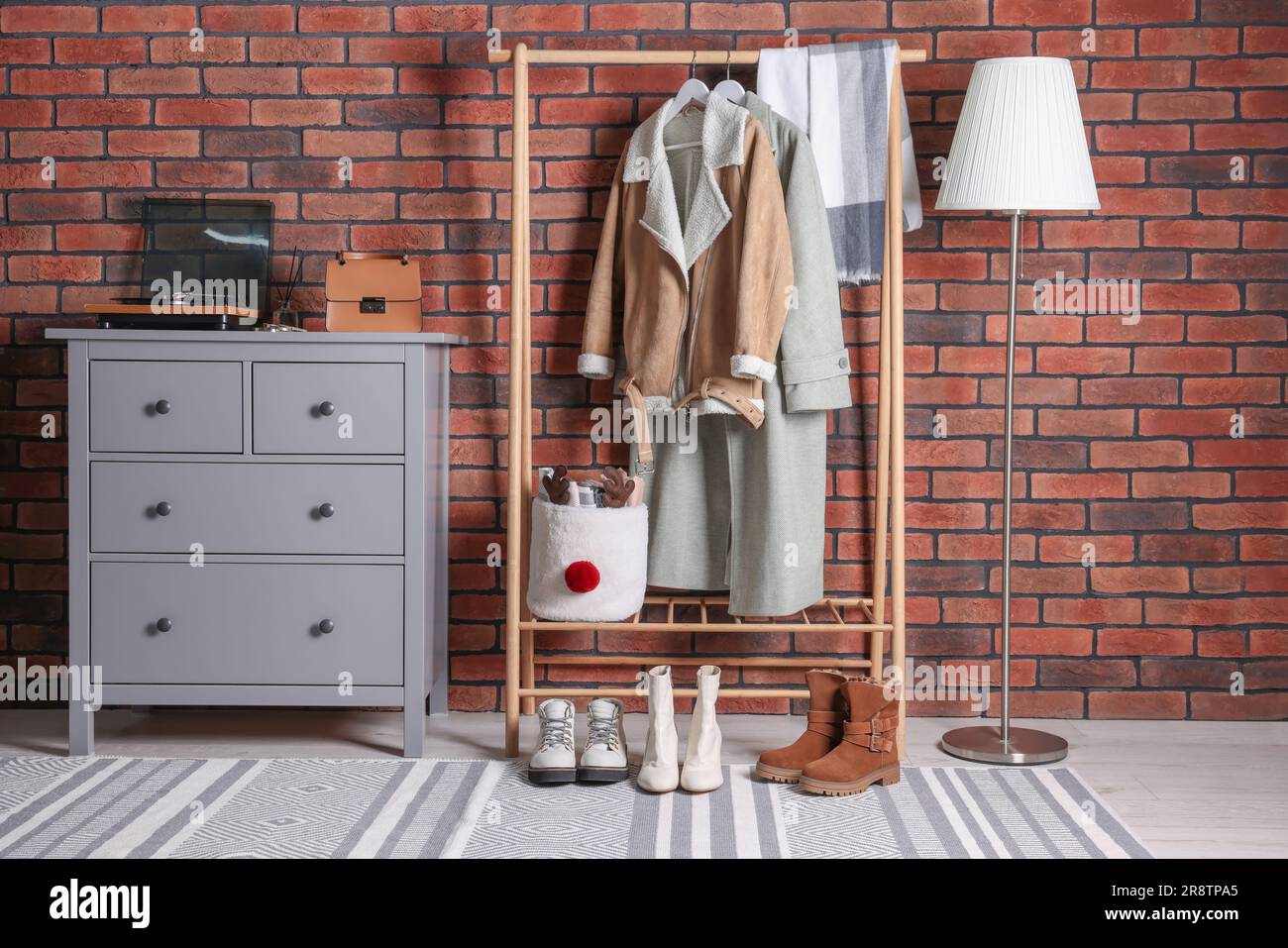 Beautiful hallway interior with coat rack and chest of drawers near red ...