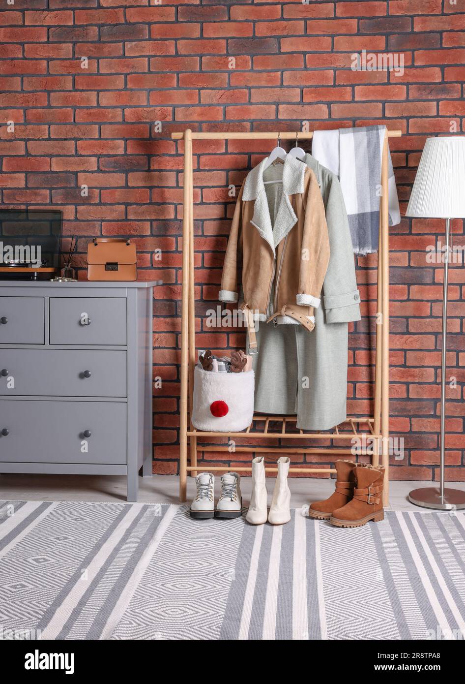 Beautiful hallway interior with coat rack and chest of drawers near red ...