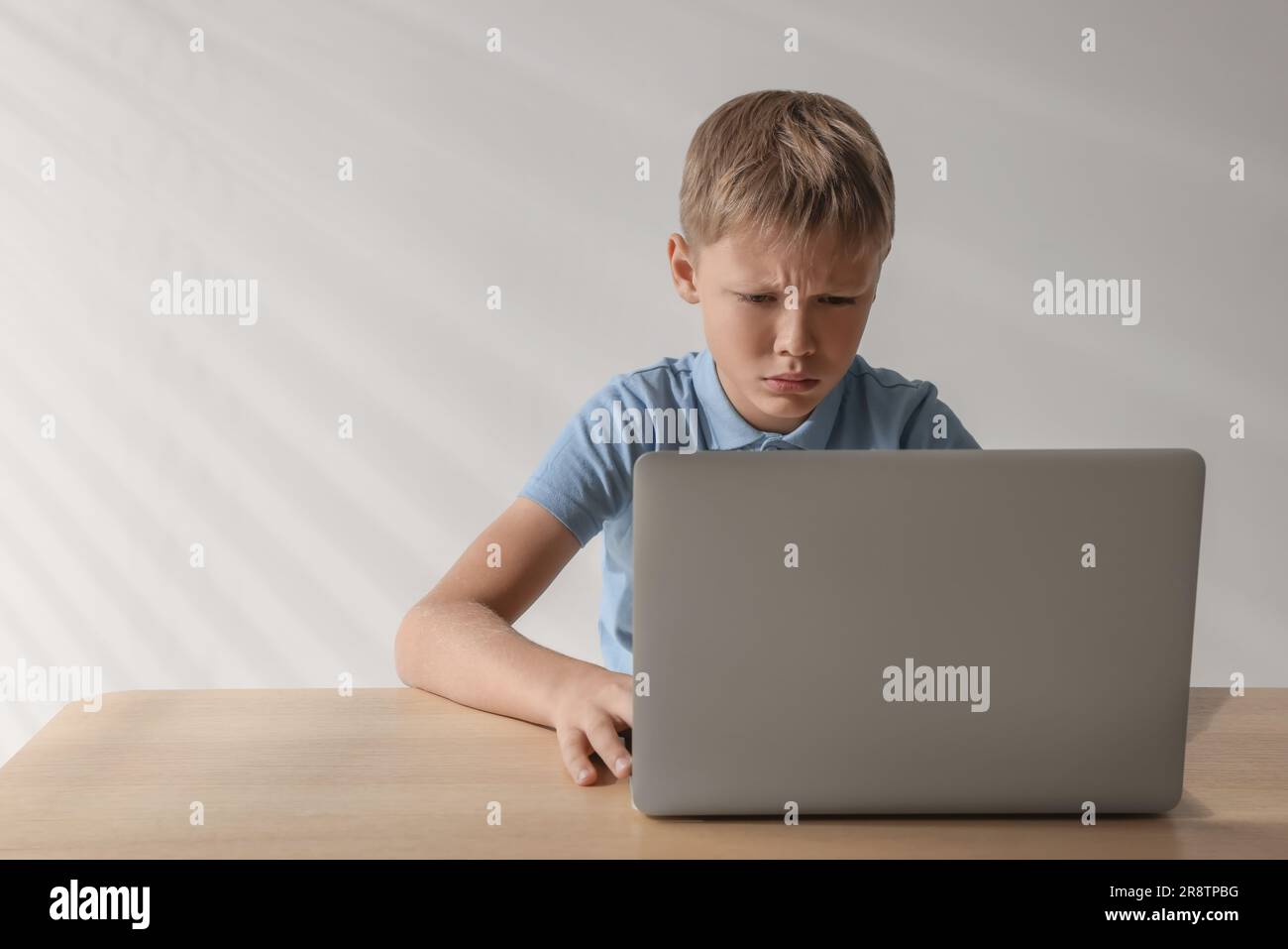 Upset boy with laptop at table, space for text. Cyber bullying Stock ...
