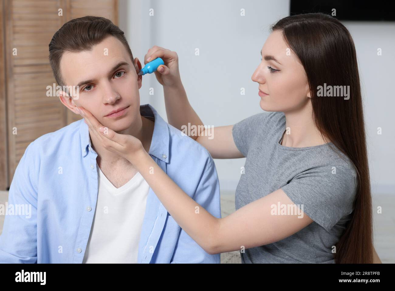 Woman dripping medication into man's ear at home Stock Photo - Alamy