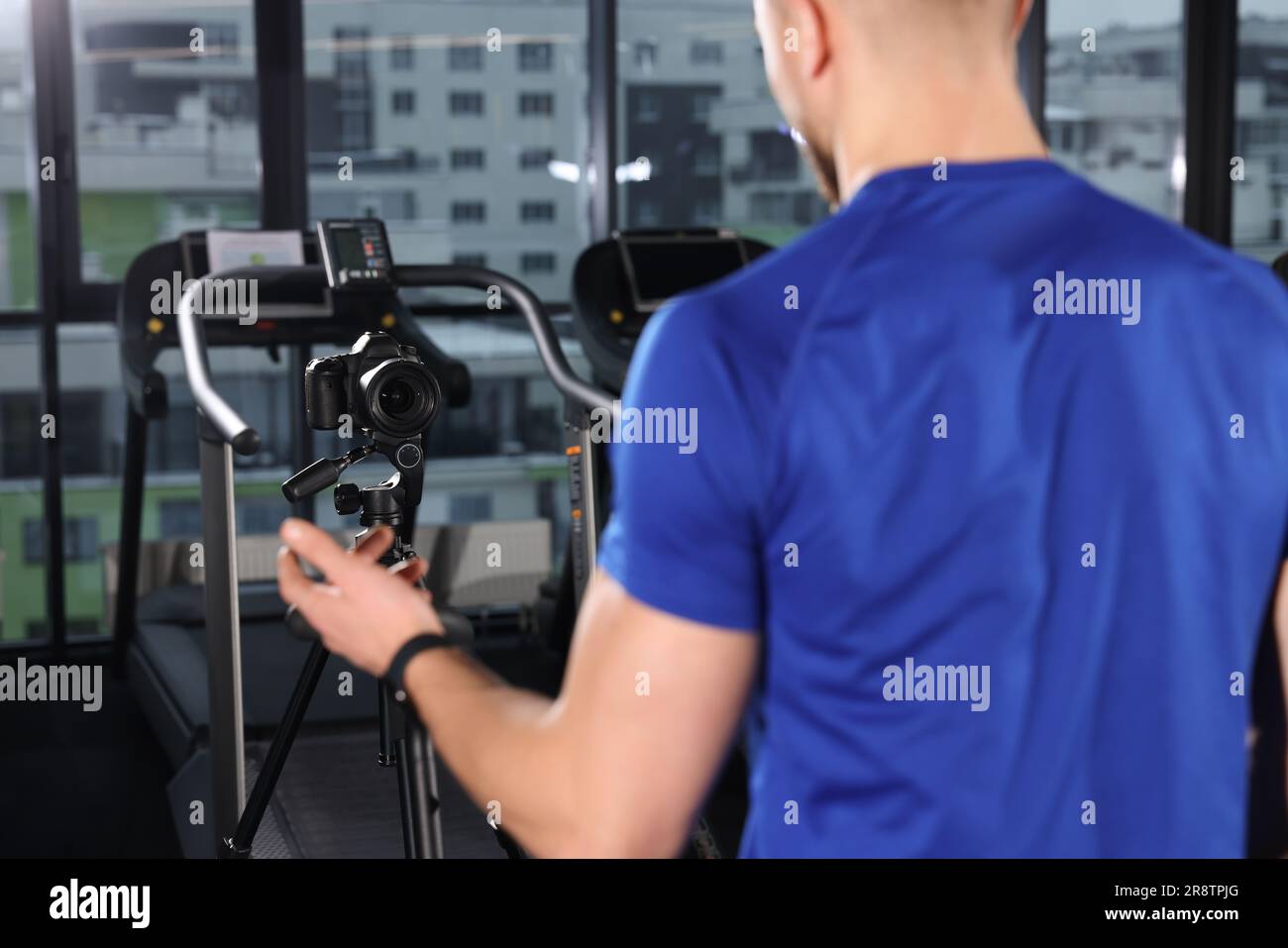 Man recording workout on camera at gym, back view. Online fitness ...