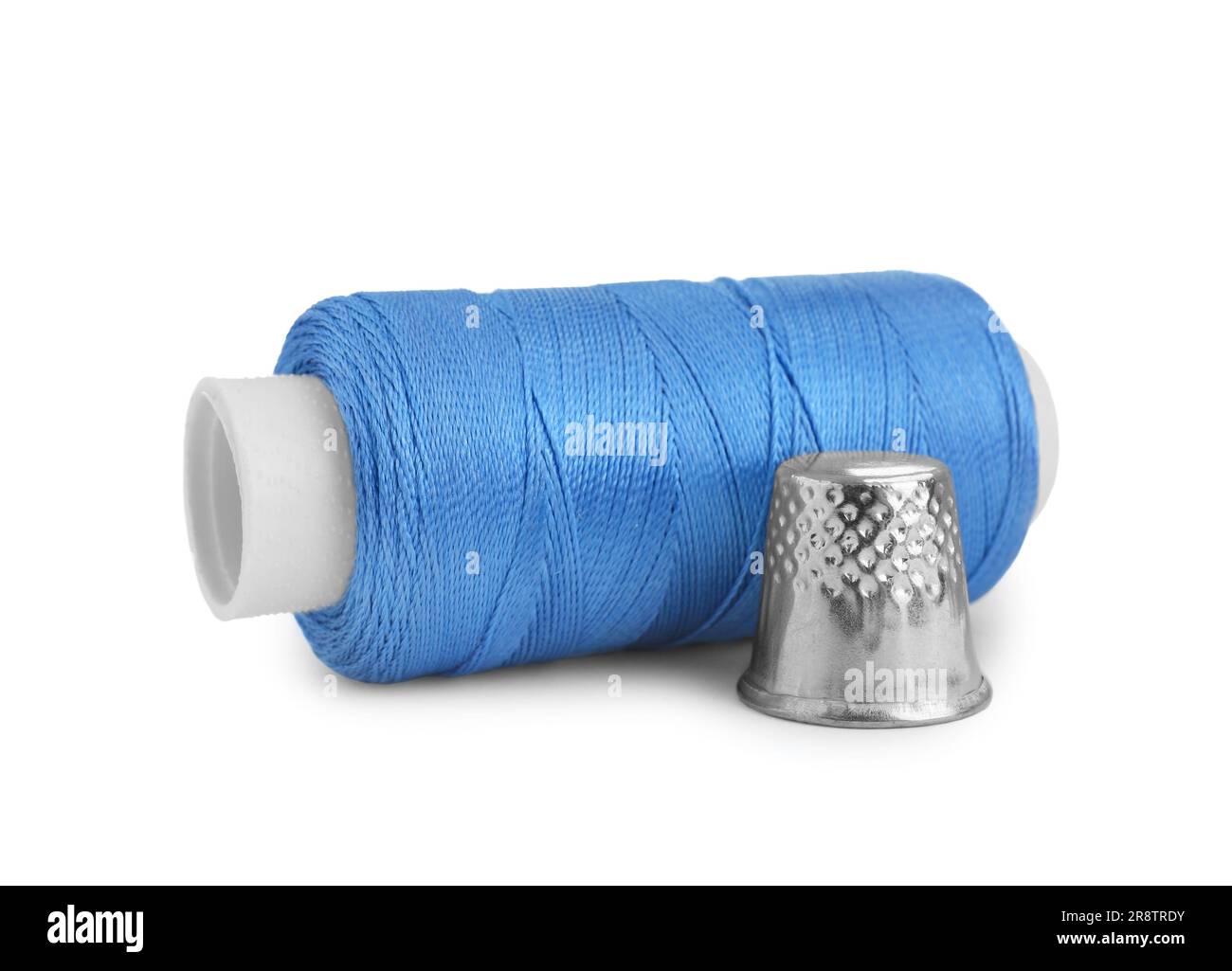 Thimble and spool of light blue sewing thread isolated on white Stock ...