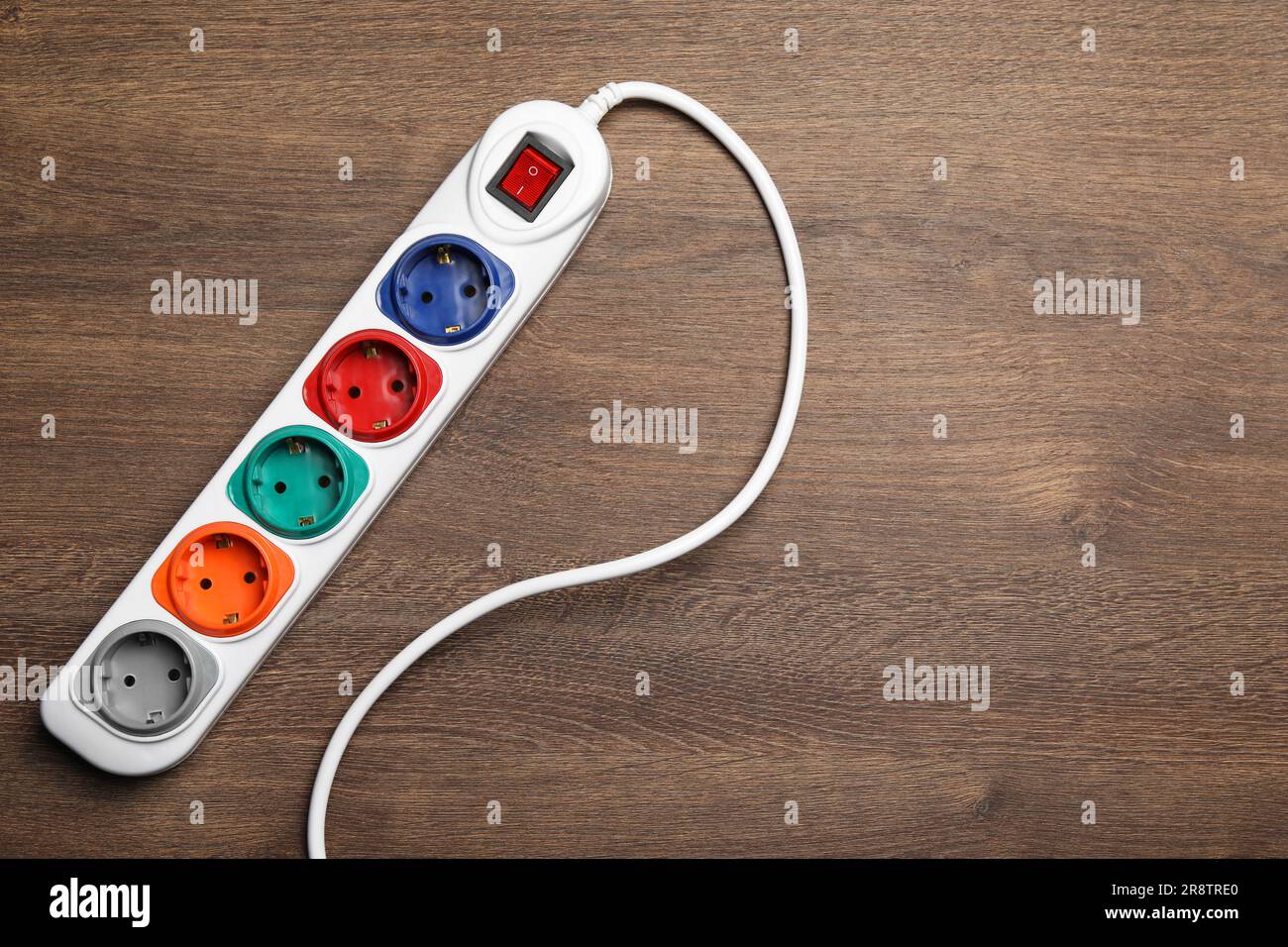 Power strip with extension cord on wooden floor, top view. Space for ...