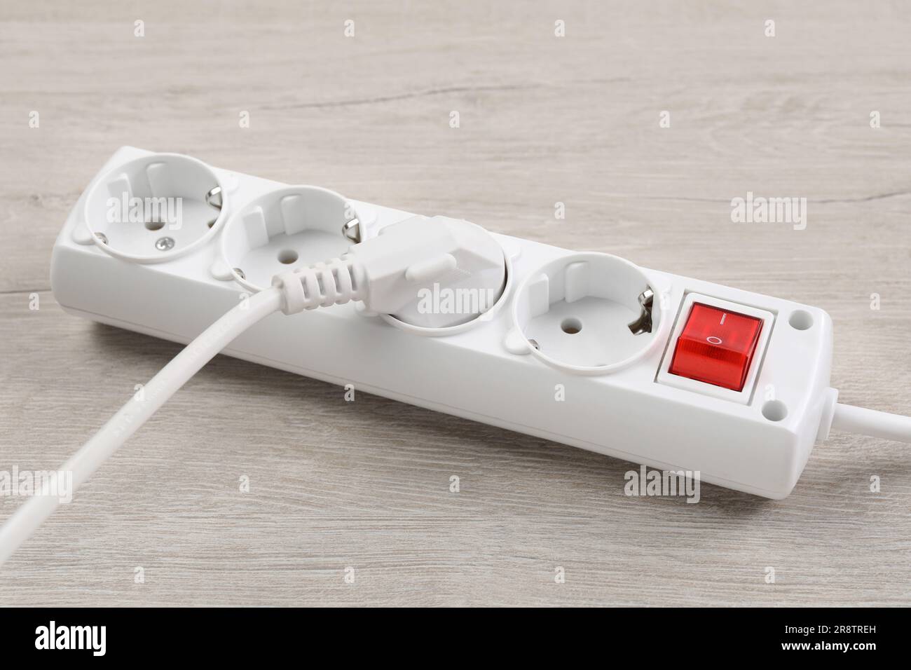 Power strip with extension cord on white wooden floor, closeup ...