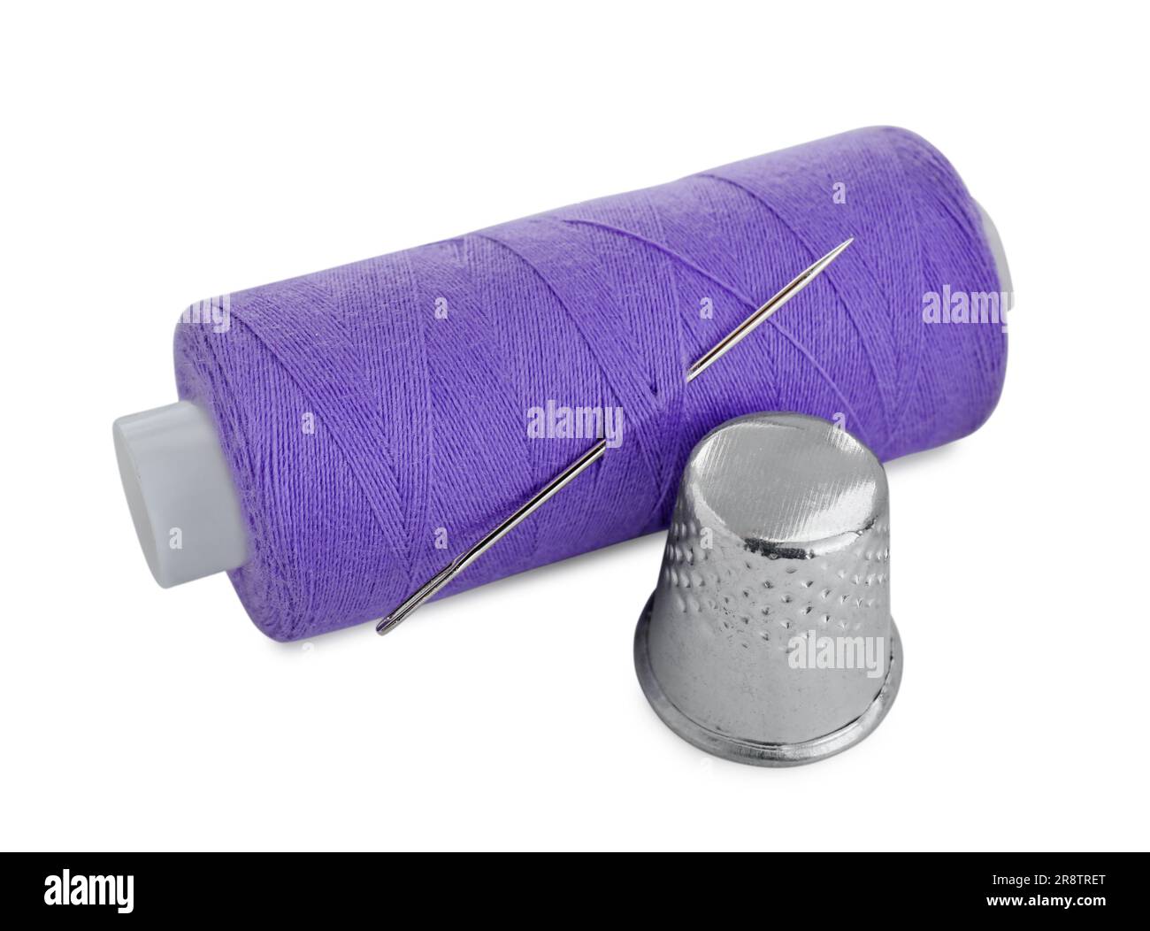Thimble and spool of purple sewing thread with needle isolated on white ...