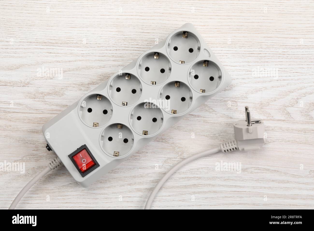 Power strip with extension cord on white wooden floor, top view ...