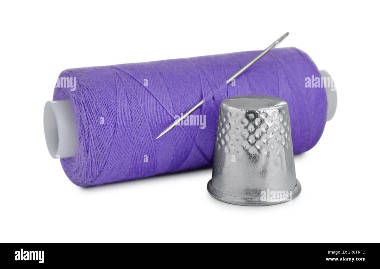 Thimble and spool of purple sewing thread with needle isolated on white ...