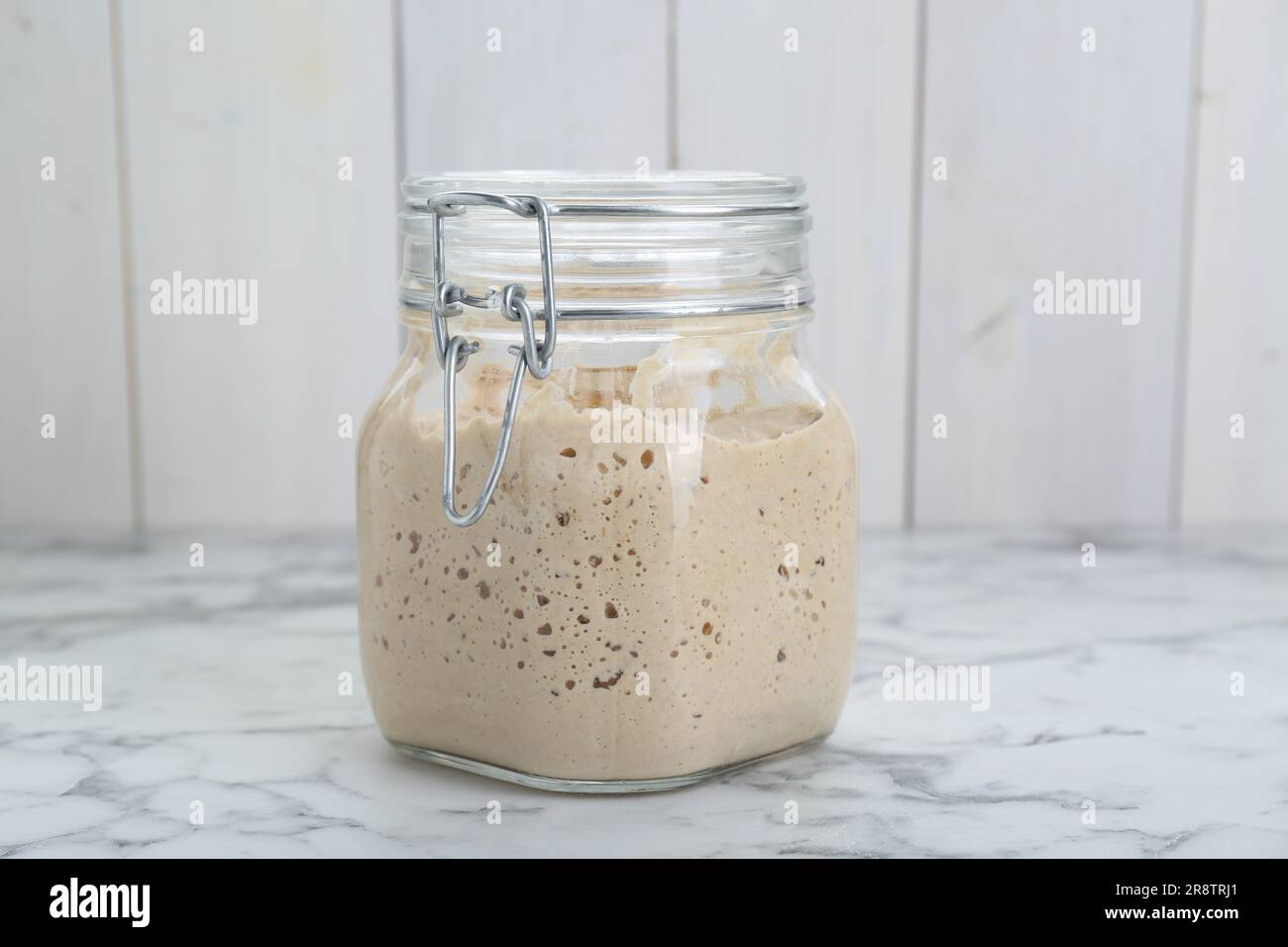 Leaven in glass jar on white marble table Stock Photo - Alamy