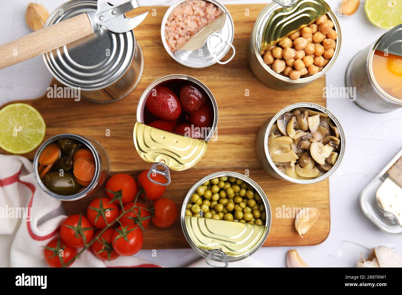 Open tin cans with different preserved products on white textured table ...