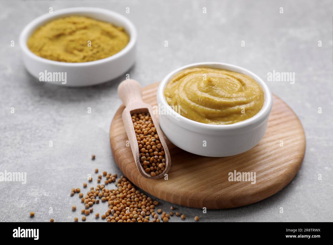Delicious mustard and seeds on light grey table Stock Photo - Alamy