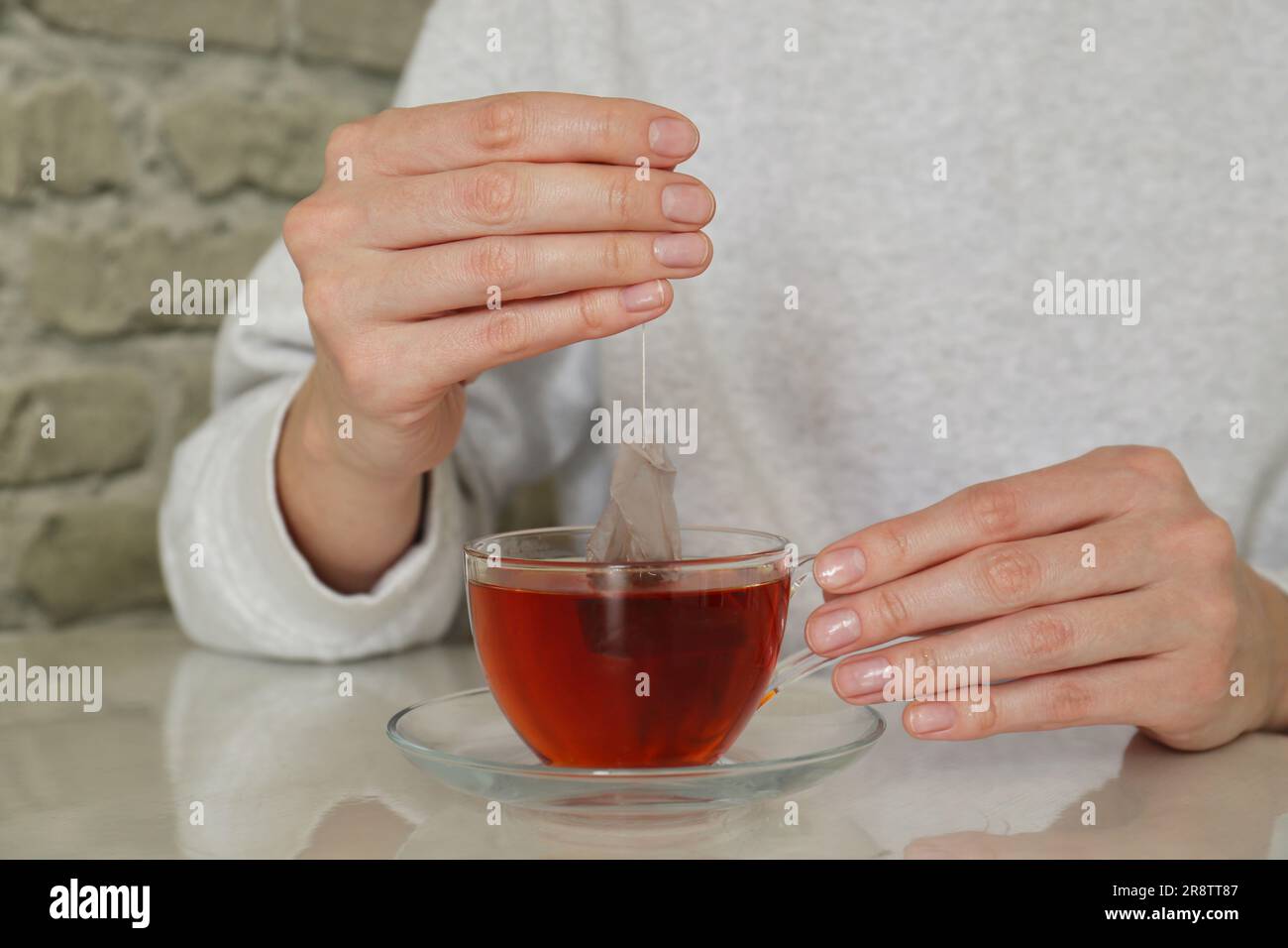 Woman taking tea bag out of cup at table indoors, closeup Stock Photo ...