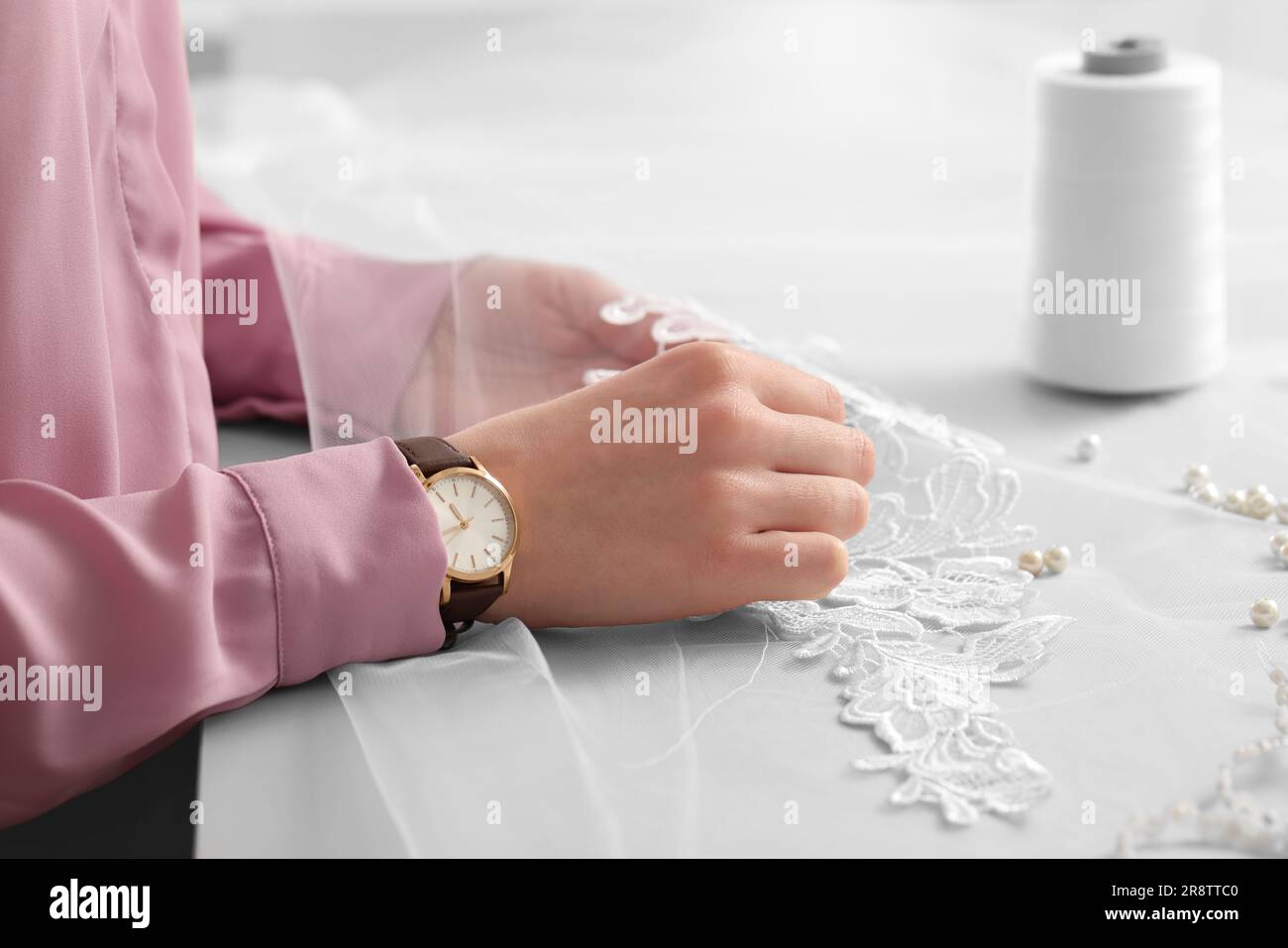 Dressmaker working with beautiful white lace at table in atelier ...