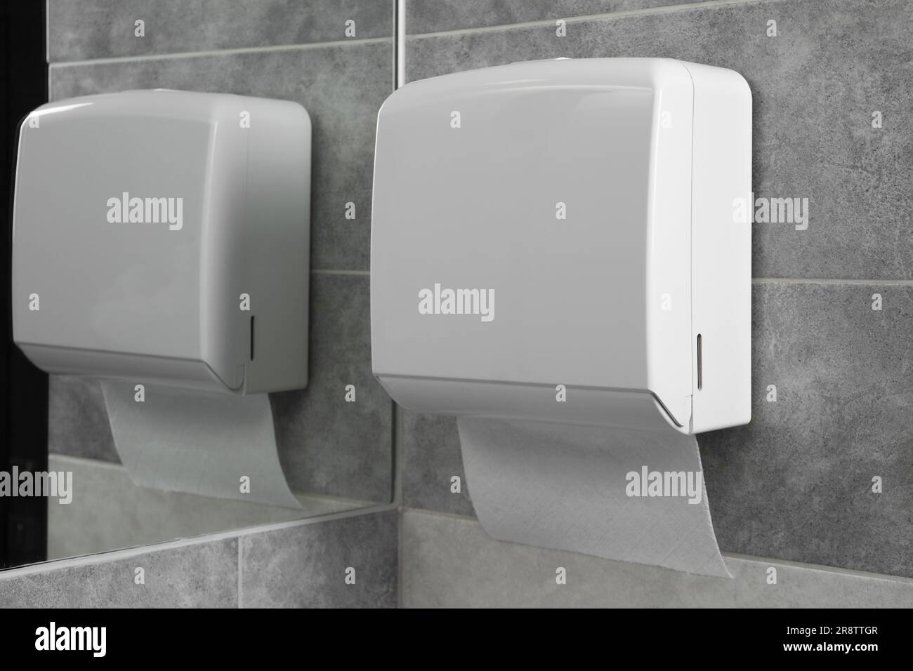 New paper towel dispenser hanging on wall near mirror in bathroom Stock ...