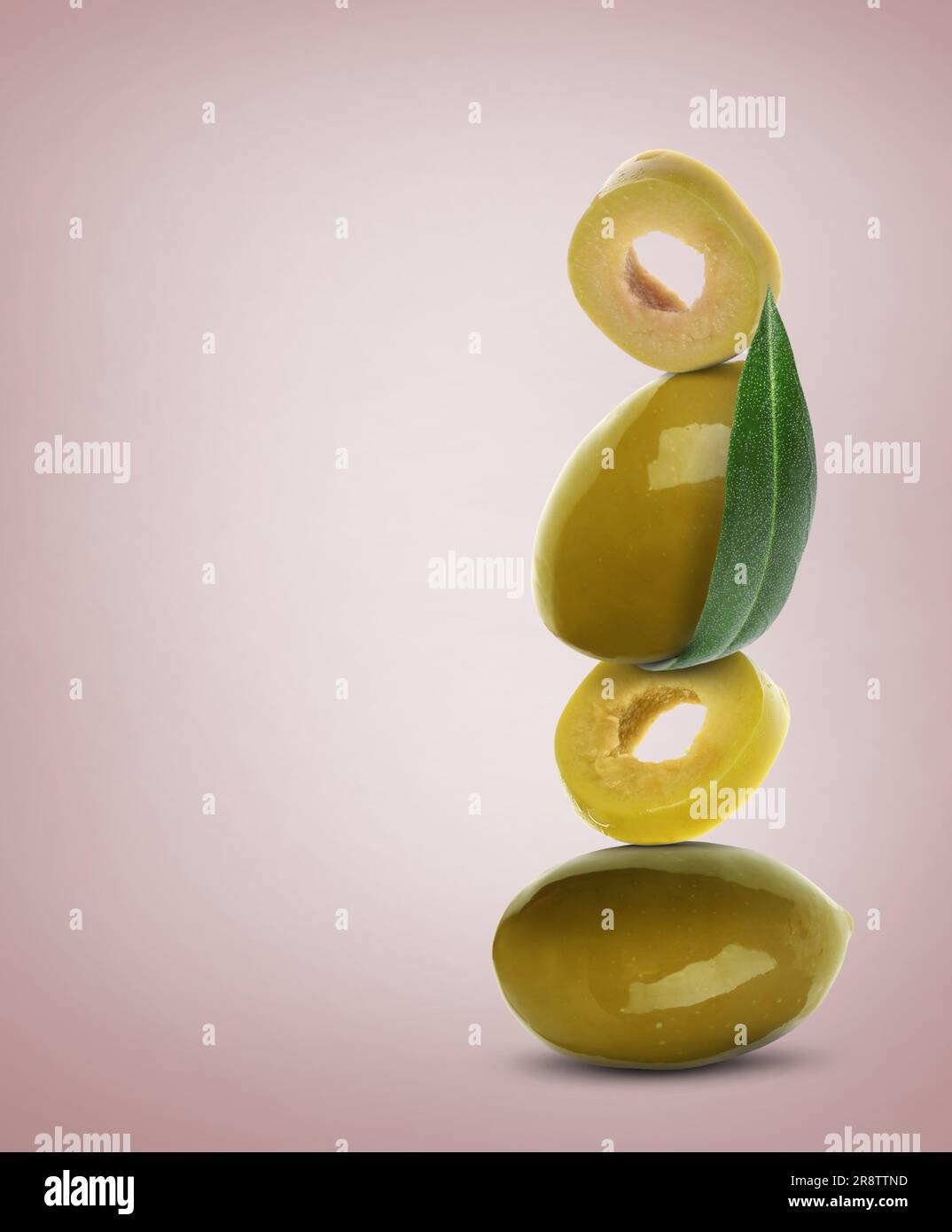 Cut and whole olives with leaf on dusty pink background, space for text ...