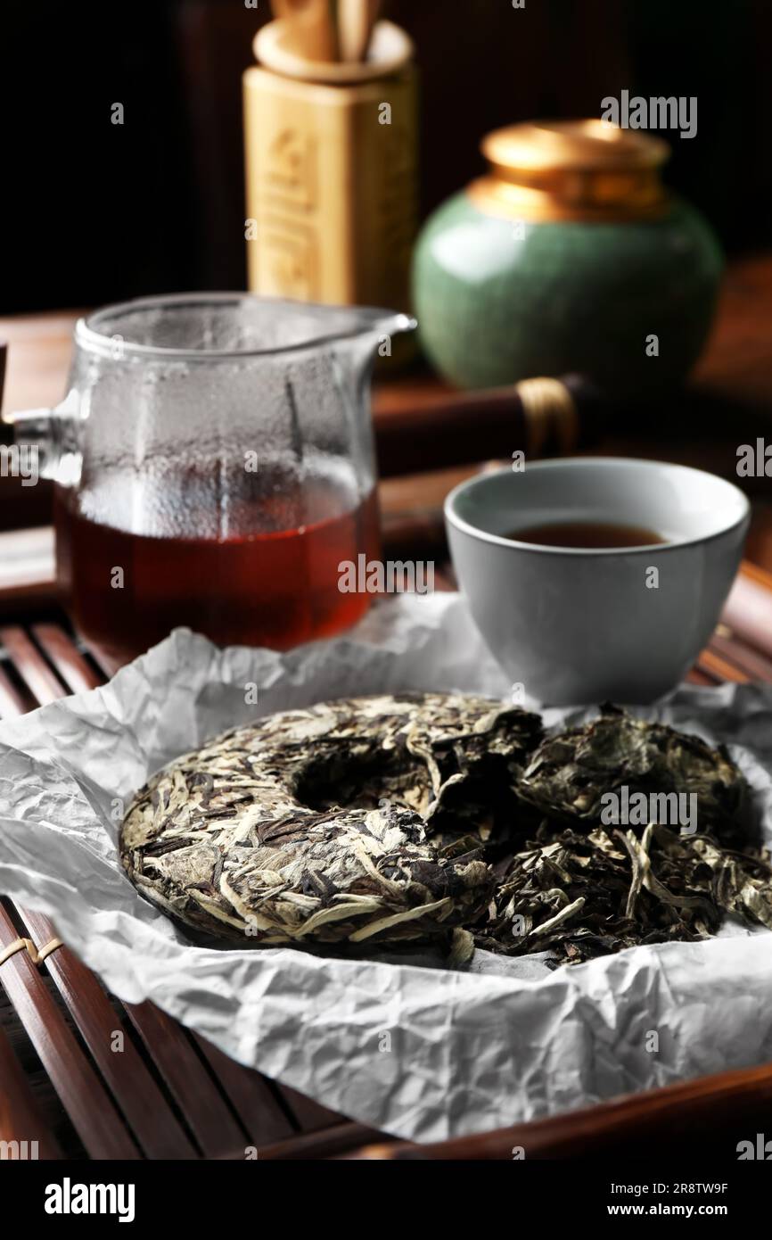 Broken disc shaped pu-erh tea on wooden tray, closeup. Traditional ...