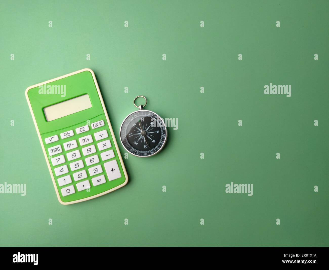 Top view green calculator with compass on a green background with copy ...