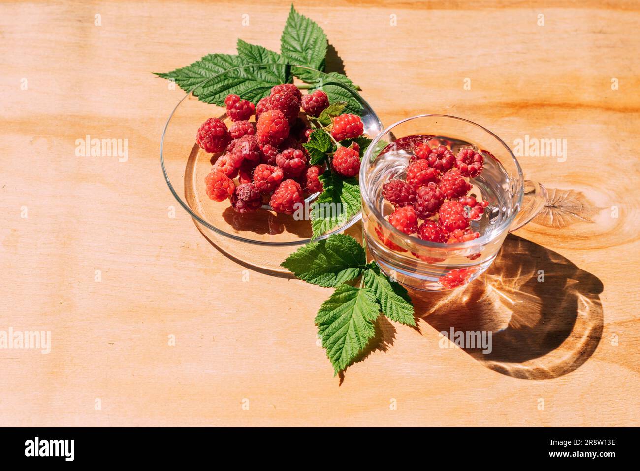 Ripe red raspberry drink in a transparent glass wooden background ...