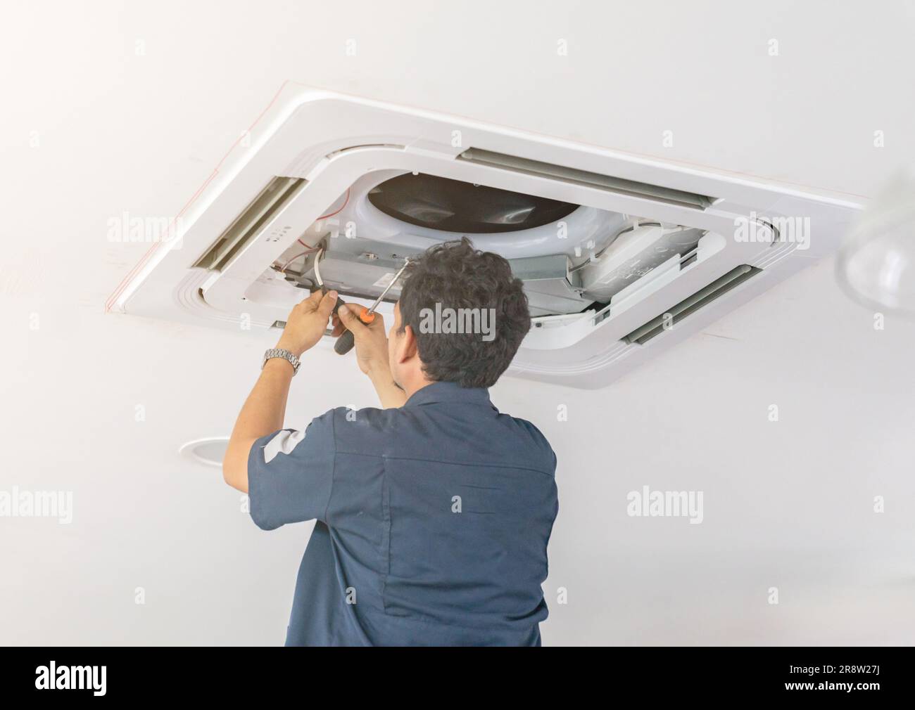 Worker repairing ceiling air conditioning unit in office Stock Photo ...