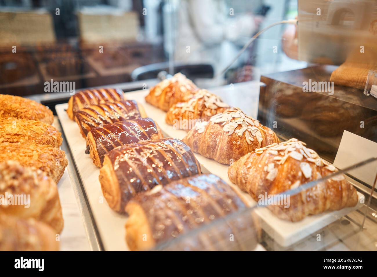 A variety of fresh pastries in the bakery window. almond croissant is ...