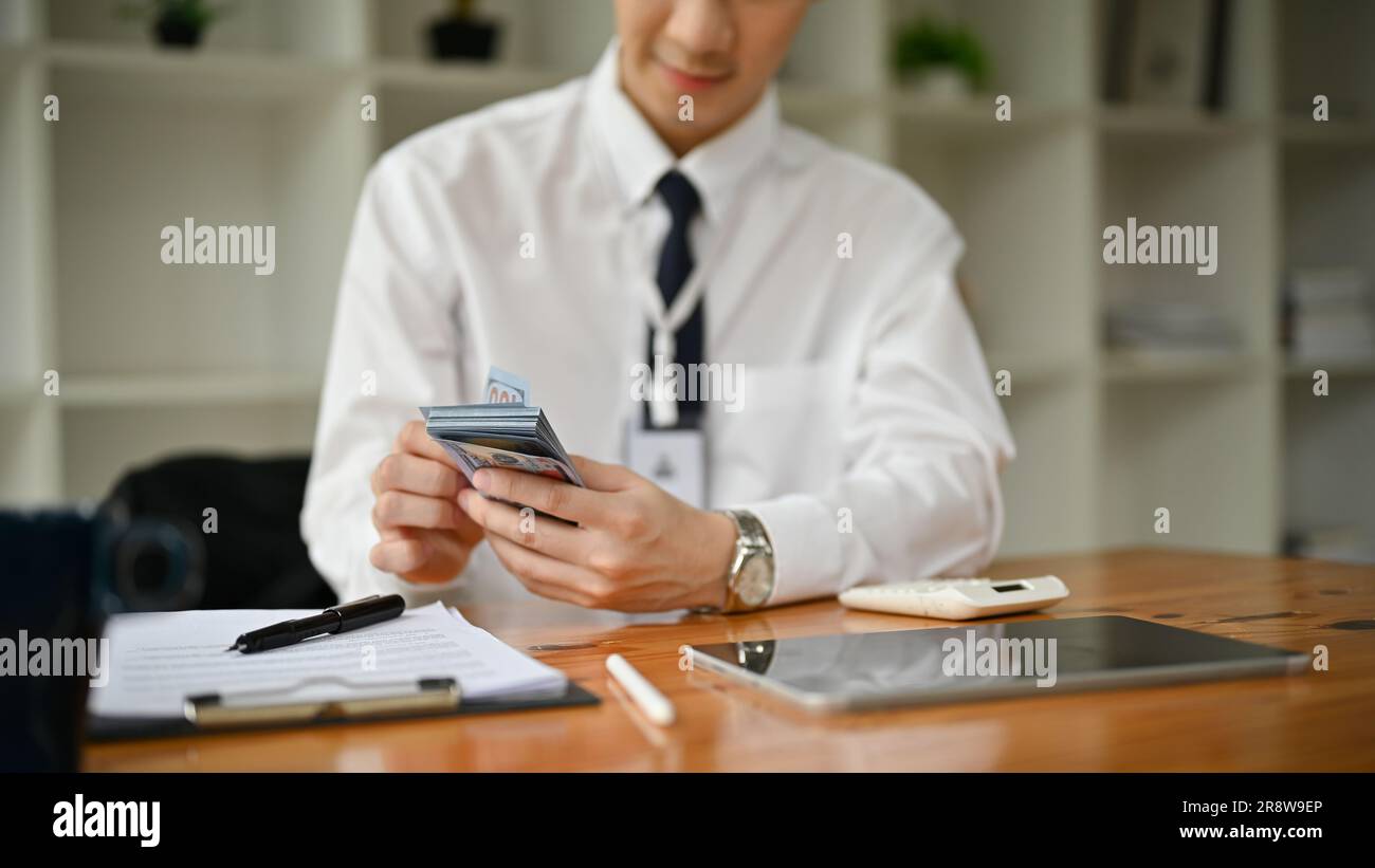 Close-up image of a professional Asian male banker counting US dollar ...