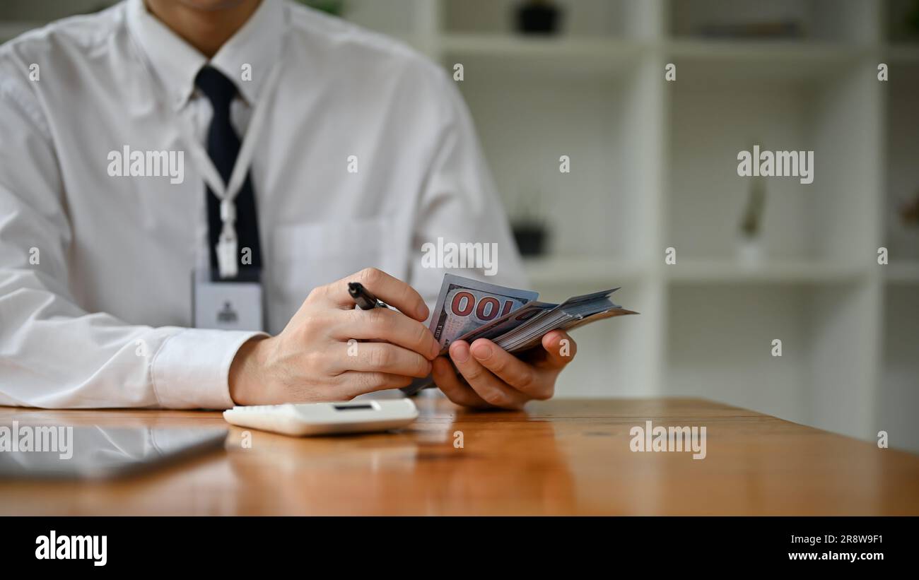 Close-up image of a professional Asian male banker counting US dollar ...