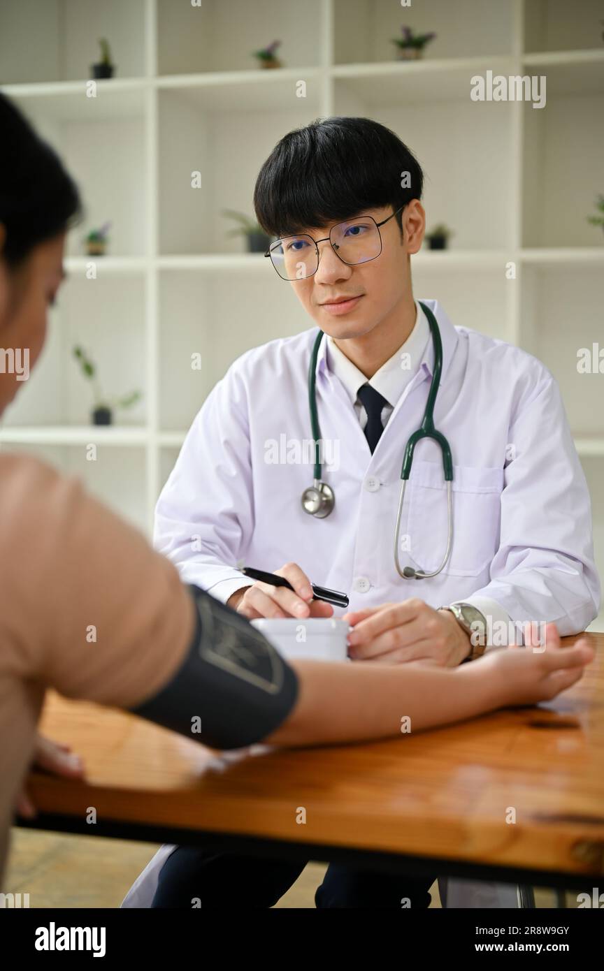 A professional millennial Asian male doctor examining a patient's heart ...