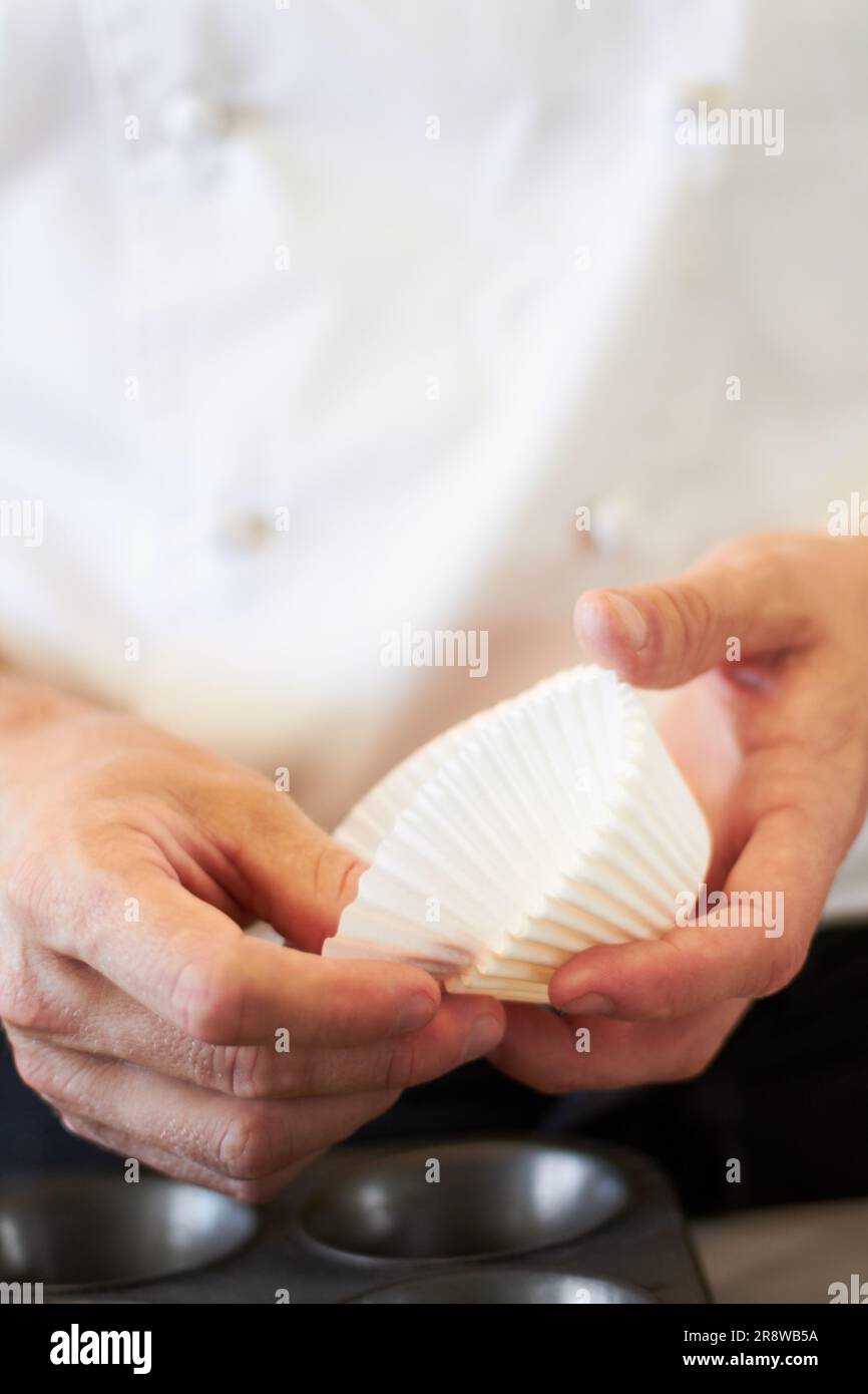 Cupcake, person hands and baking in a kitchen with muffin wrapper and ...