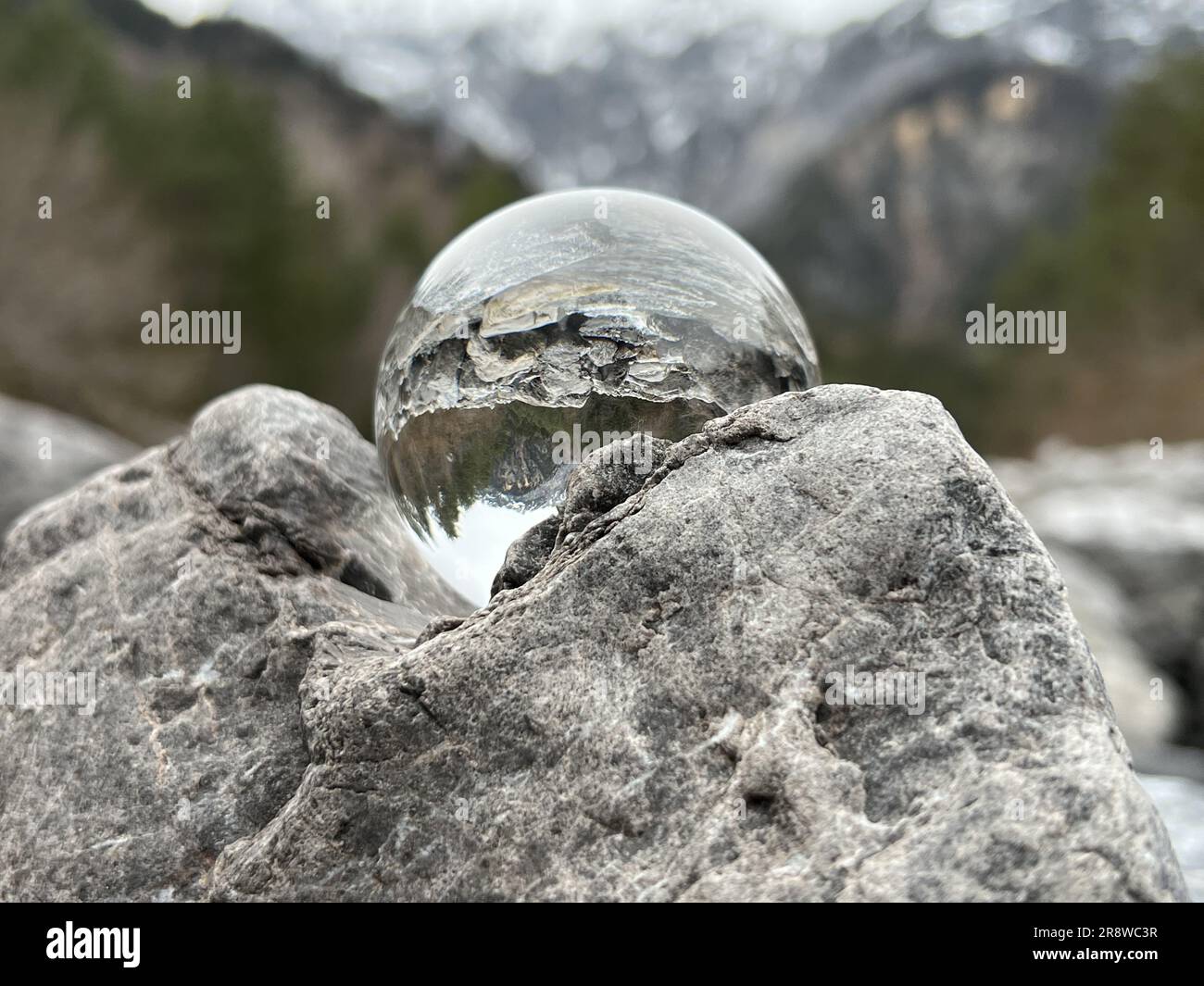 Lensball, crystal ball on rocks, reflecting an alpine creek, in the ...