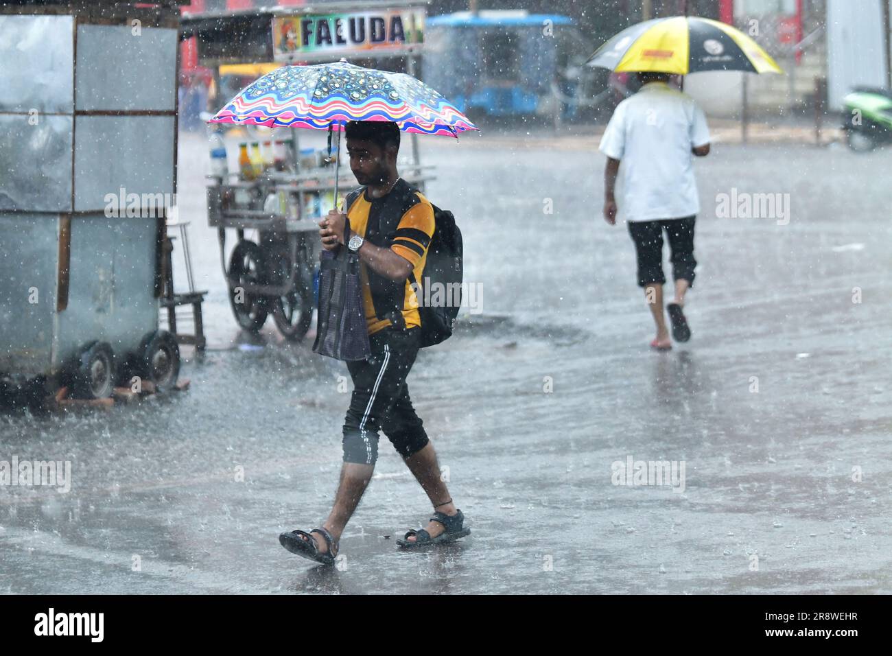 Commuters make their way on a waterlogged street during heavy rains in ...
