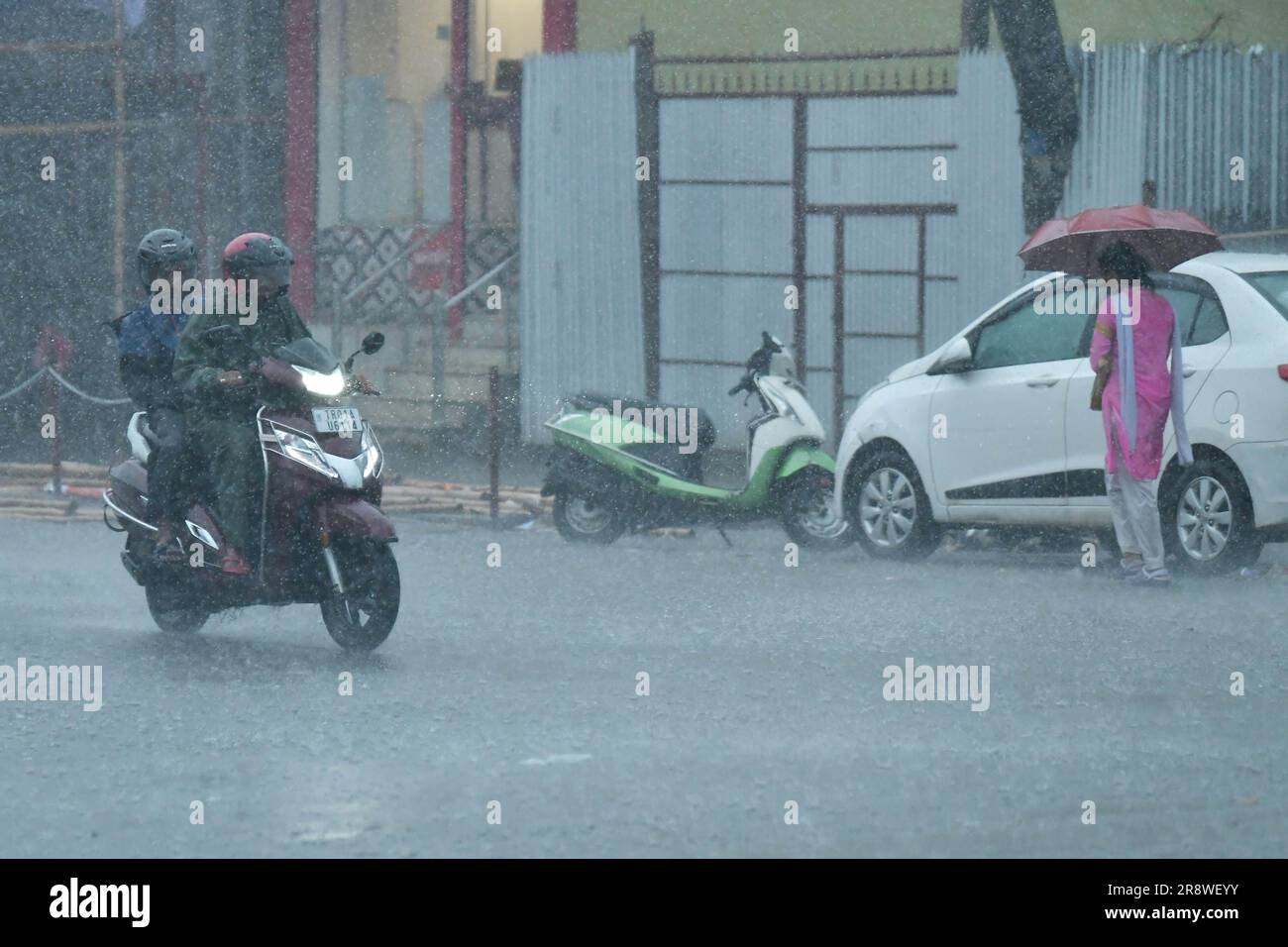 Commuters make their way on a waterlogged street during heavy rains in ...