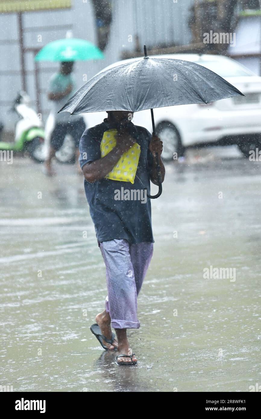 Commuters make their way on a waterlogged street during heavy rains in ...