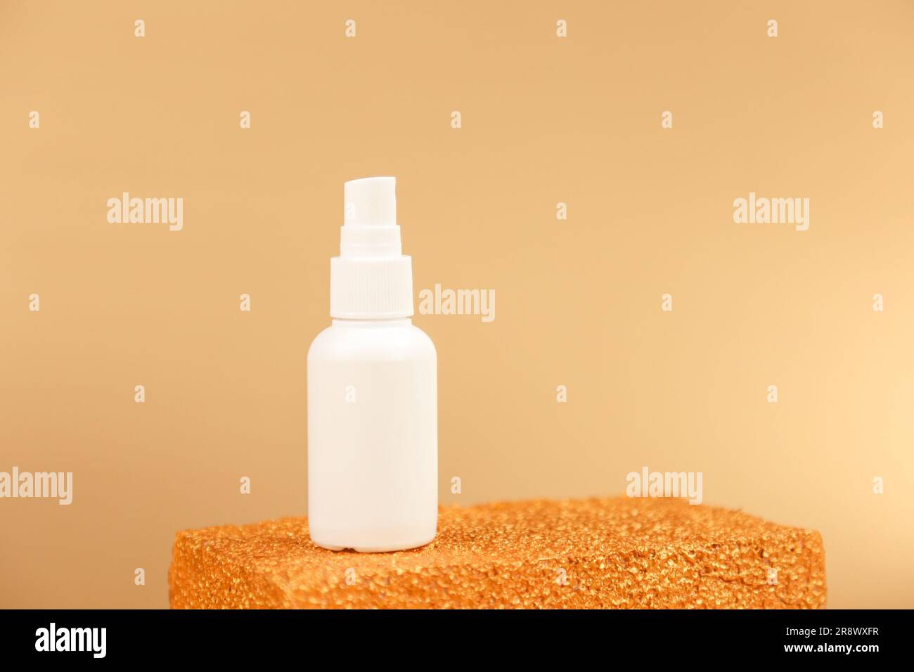 Unbranded white cosmetics spray bottle on golden podium on gold ...