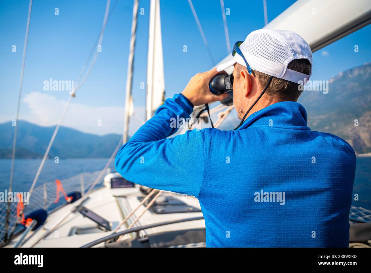 Young man captain on the yacht looking through binoculars during ...