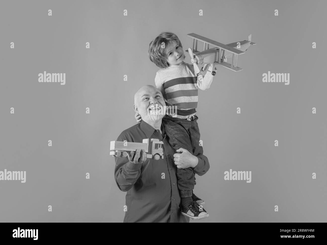 Young grandson and old grandfather piggyback with toy plane and wooden ...