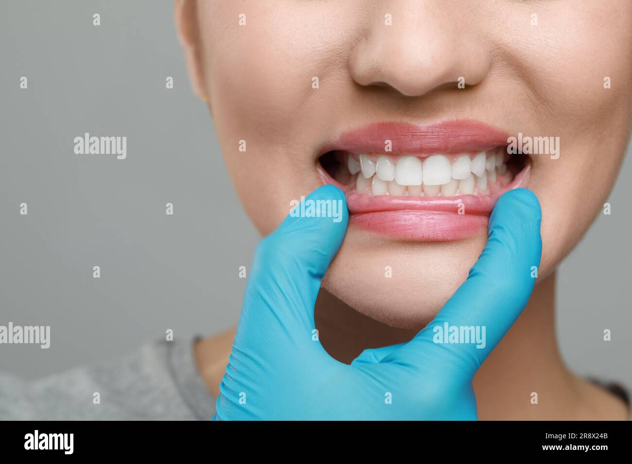 Doctor examining woman's gums on grey background, closeup Stock Photo ...