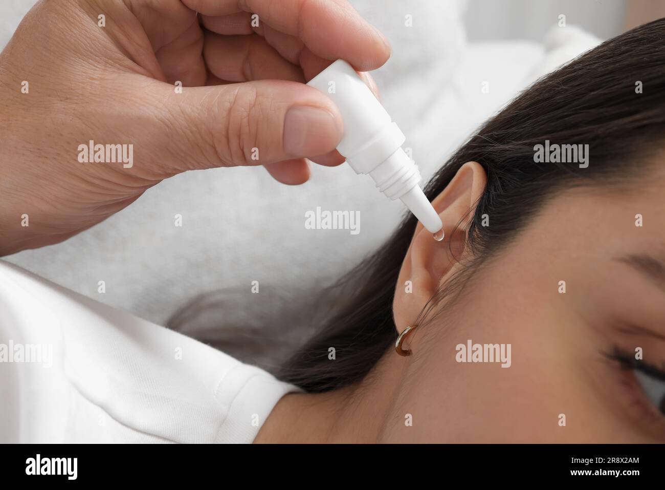 Senior man dripping medication into woman's ear on sofa, closeup Stock ...