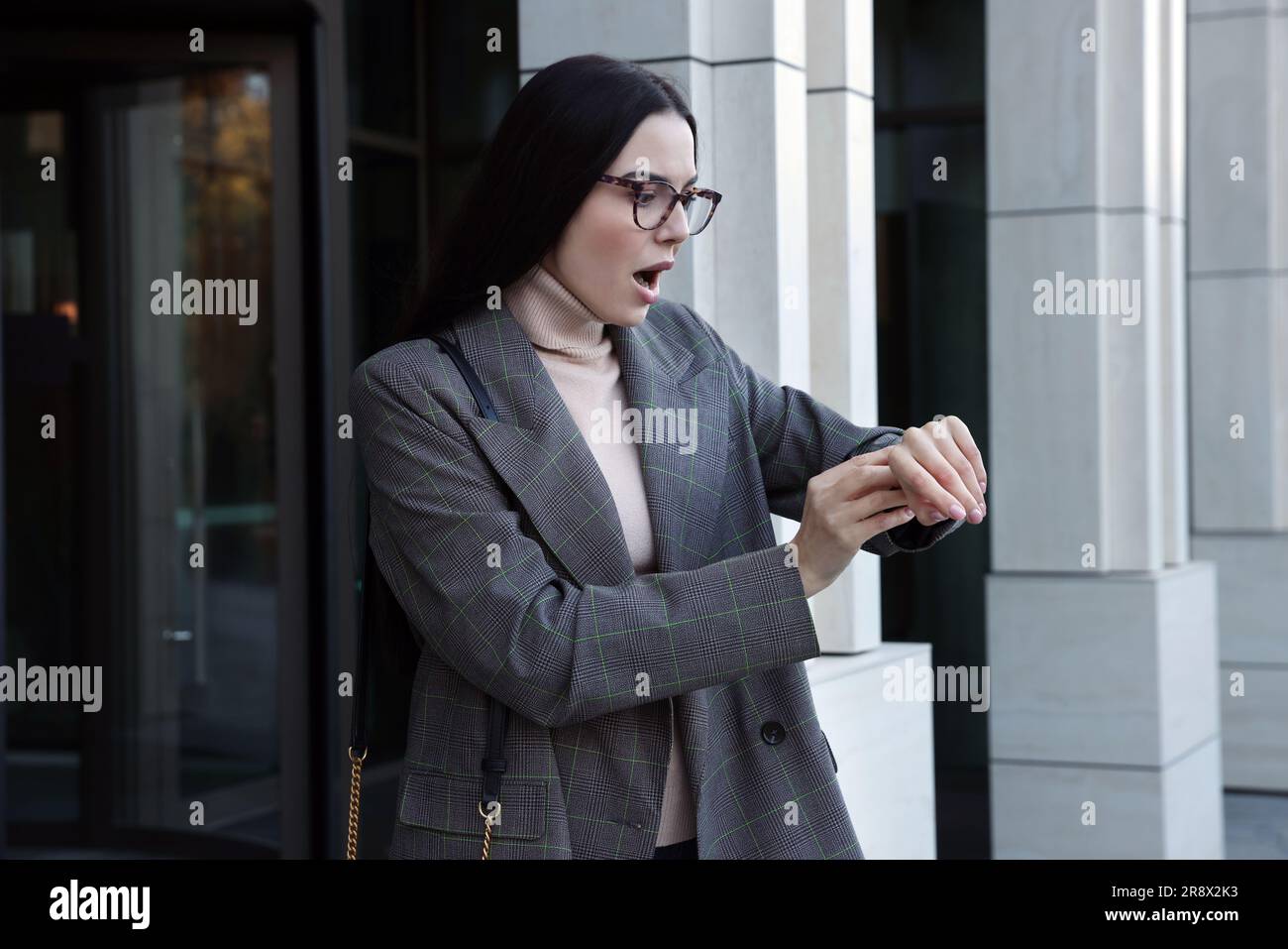 Emotional woman checking time on watch outdoors. Being late concept ...
