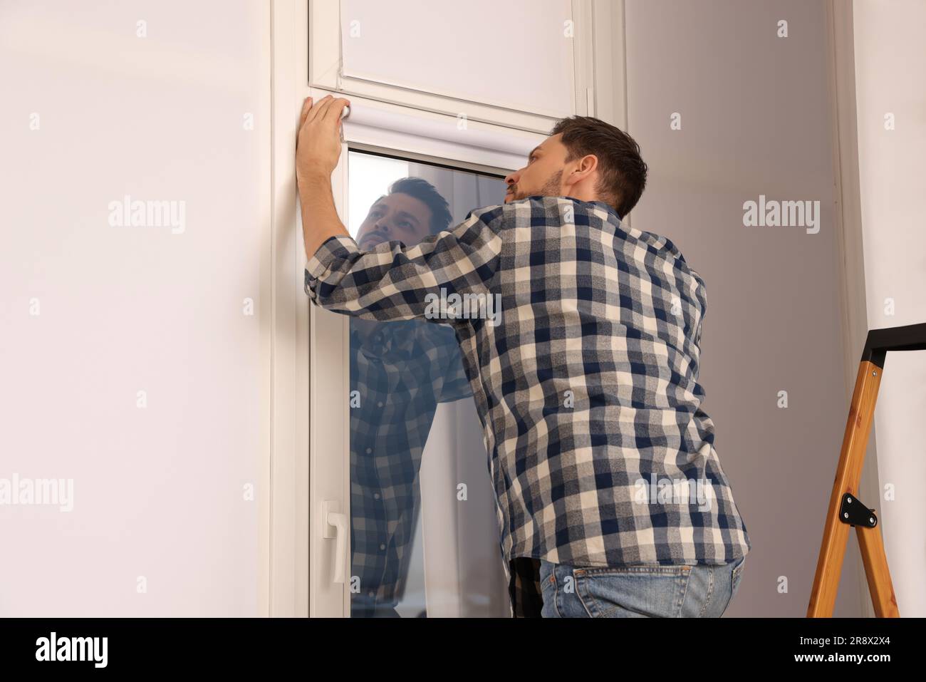 Man installing modern roller window blind indoors Stock Photo - Alamy