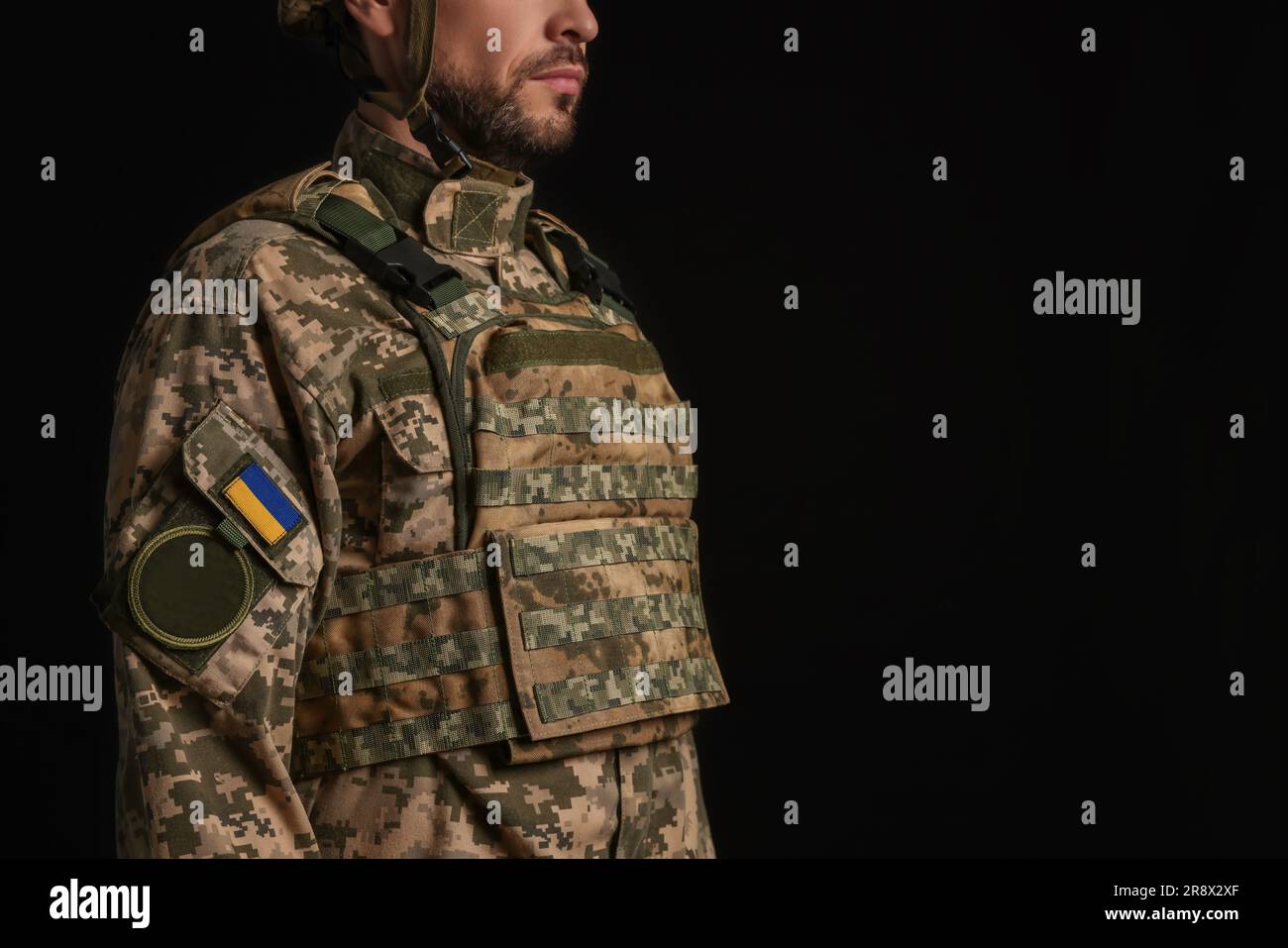 Soldier in Ukrainian military uniform on black background, closeup ...