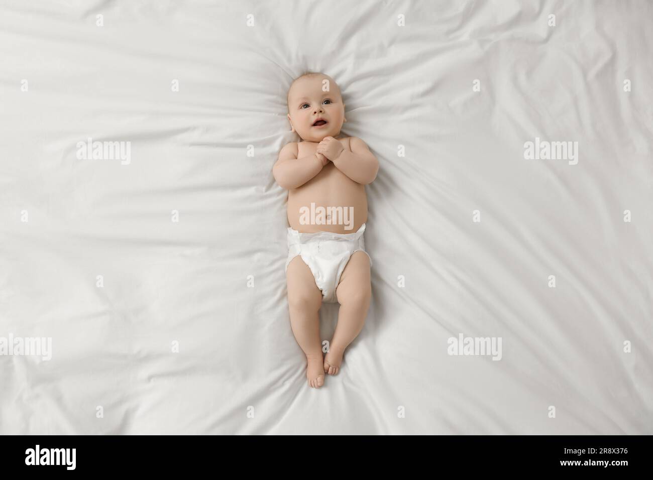 Cute little baby in diaper lying on white bed, top view Stock Photo - Alamy