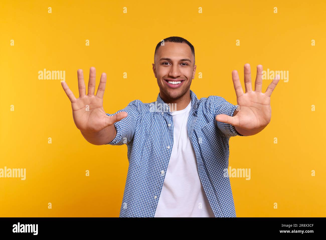 Man giving high five with both hands on yellow background Stock Photo ...