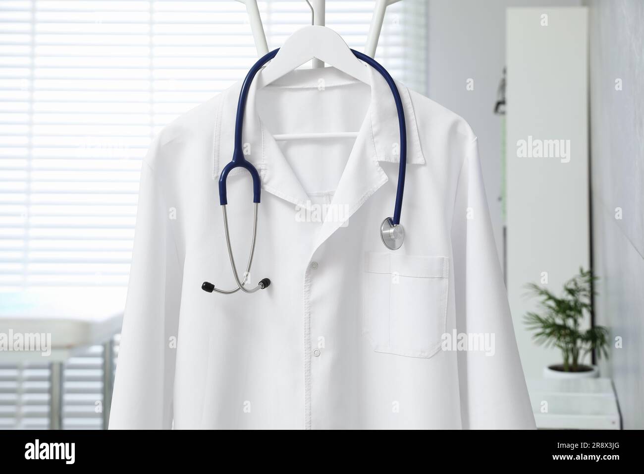 White doctor's gown and stethoscope hanging on rack in clinic, closeup ...