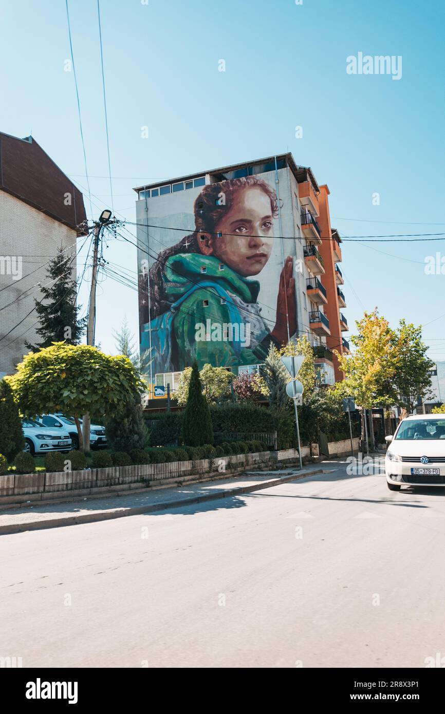 a mural of a young girl on the side of an apartment block in the city ...