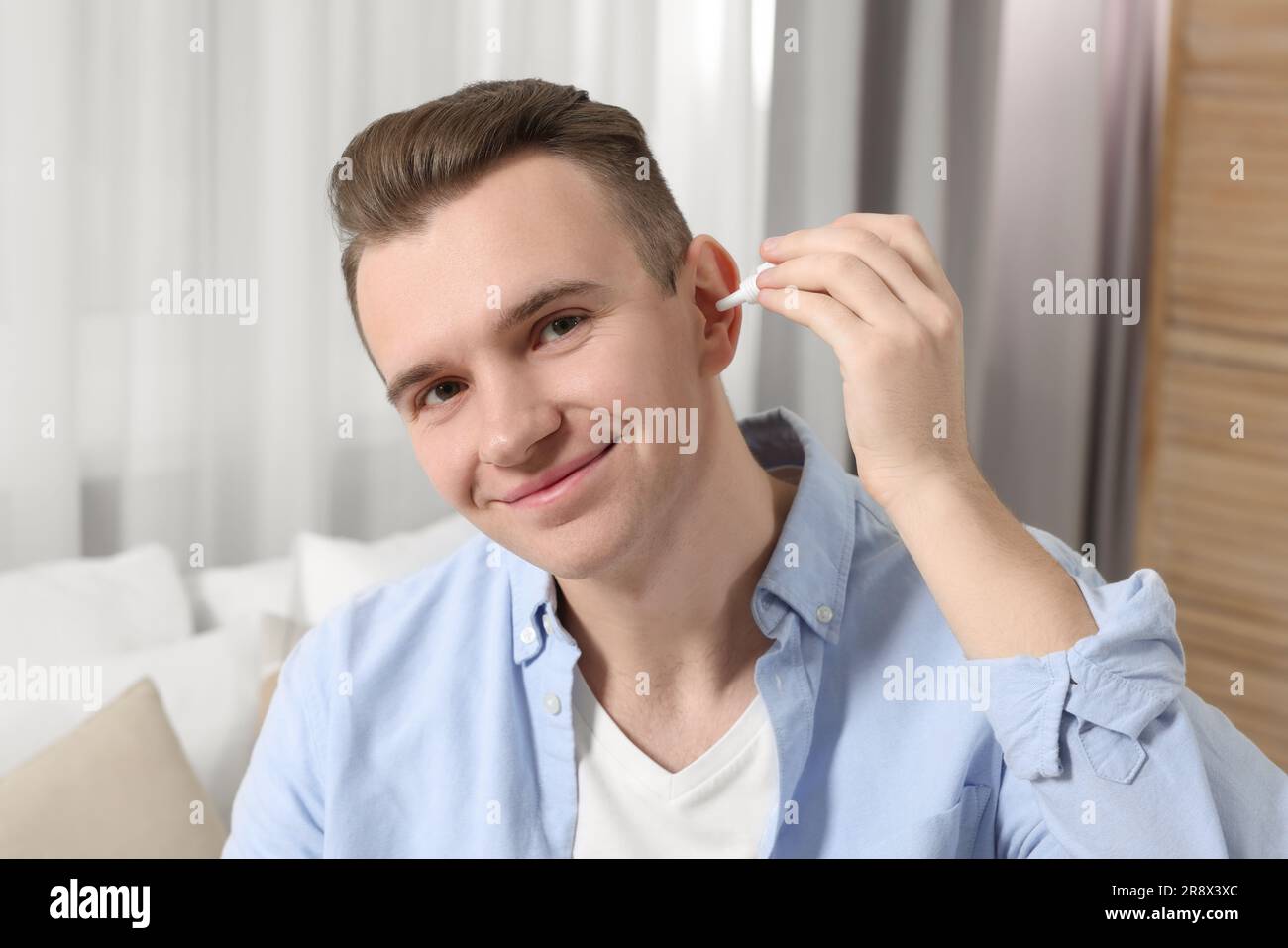 Young man using ear drops at home Stock Photo - Alamy