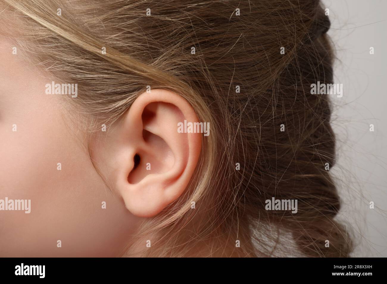 Closeup view of little girl against light gray background, focus on ear ...